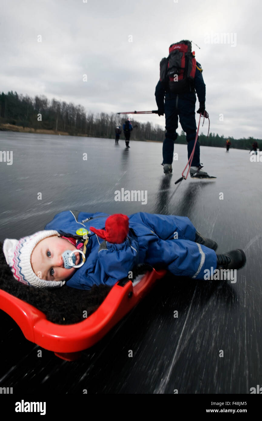 Man skating with a child in a little sledge, Sweden Stock Photo - Alamy