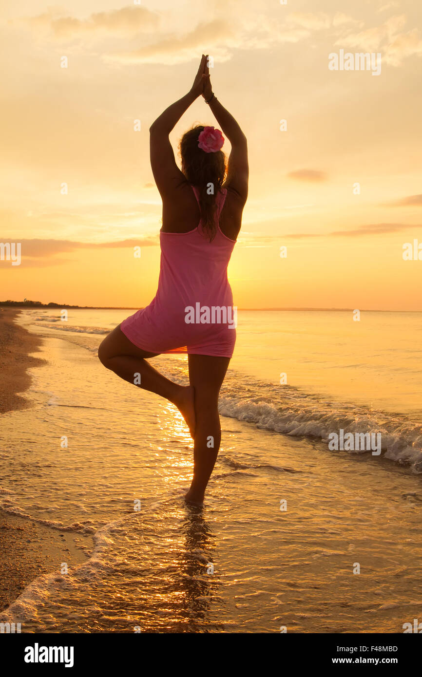 Young girl the beach at sunrise doing yoga exercise Stock Photo - Alamy