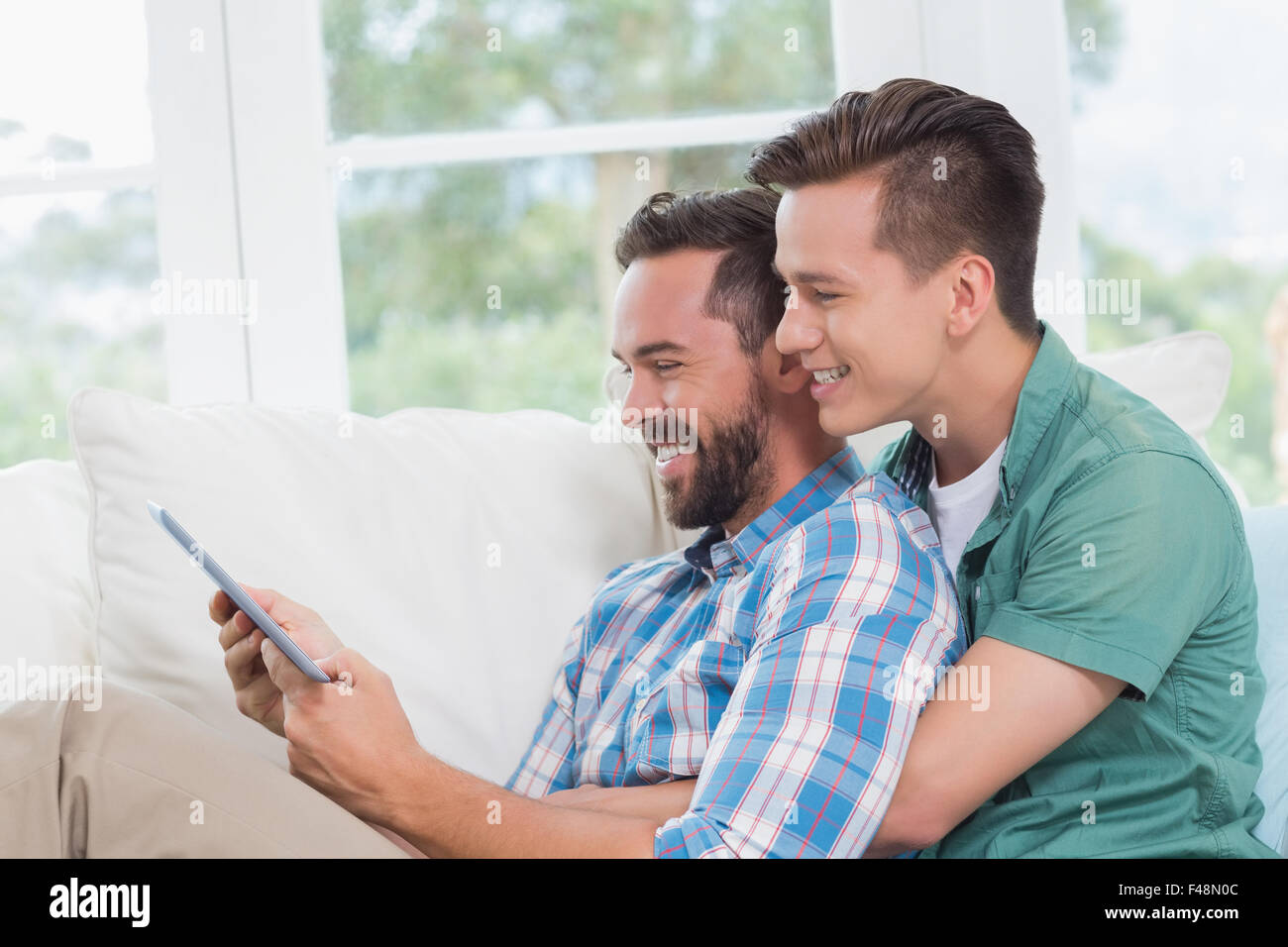 Homosexual couple men looking at tablet Stock Photo - Alamy