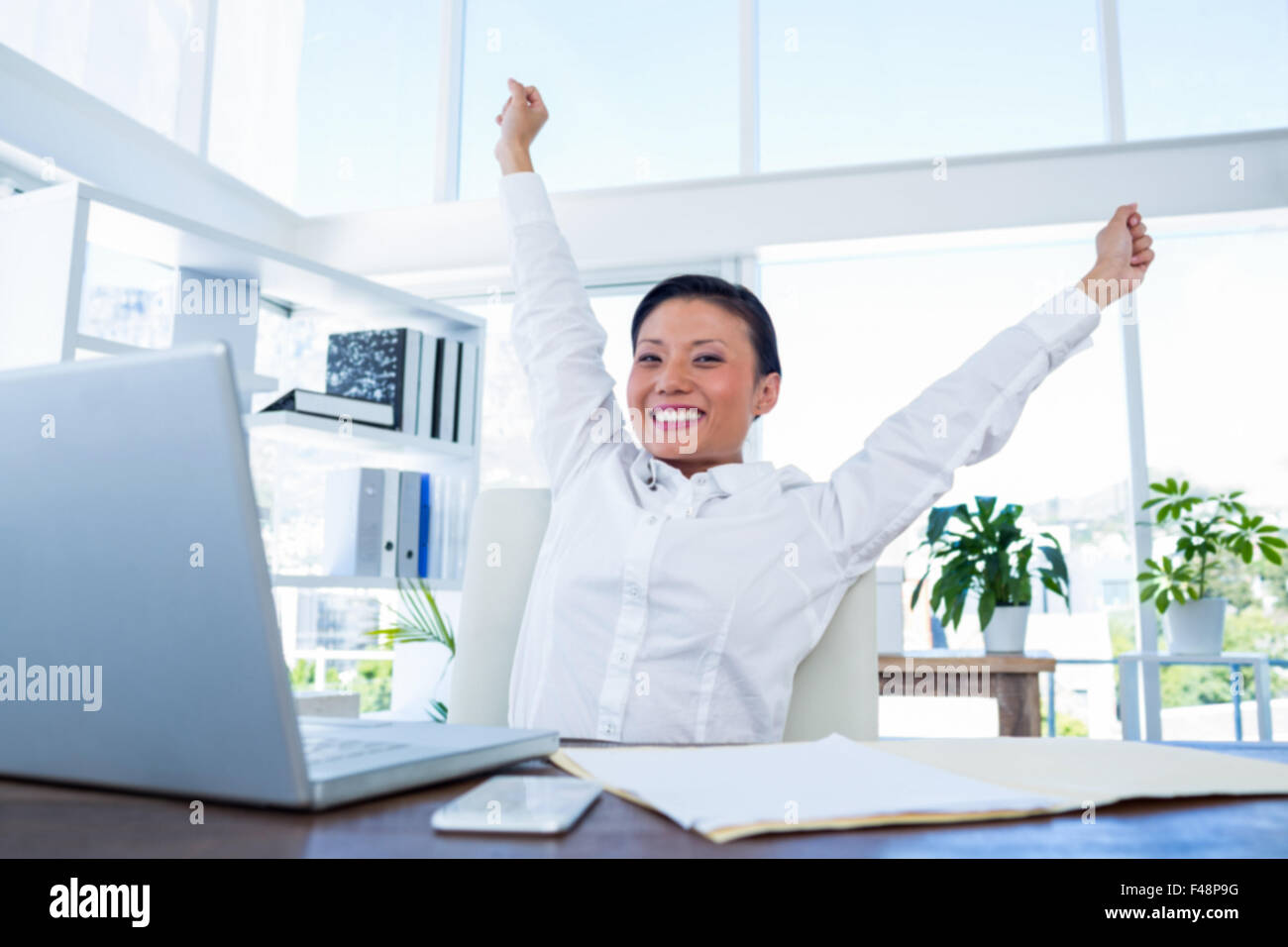 Businesswoman cheering behind laptop computer Stock Photo - Alamy