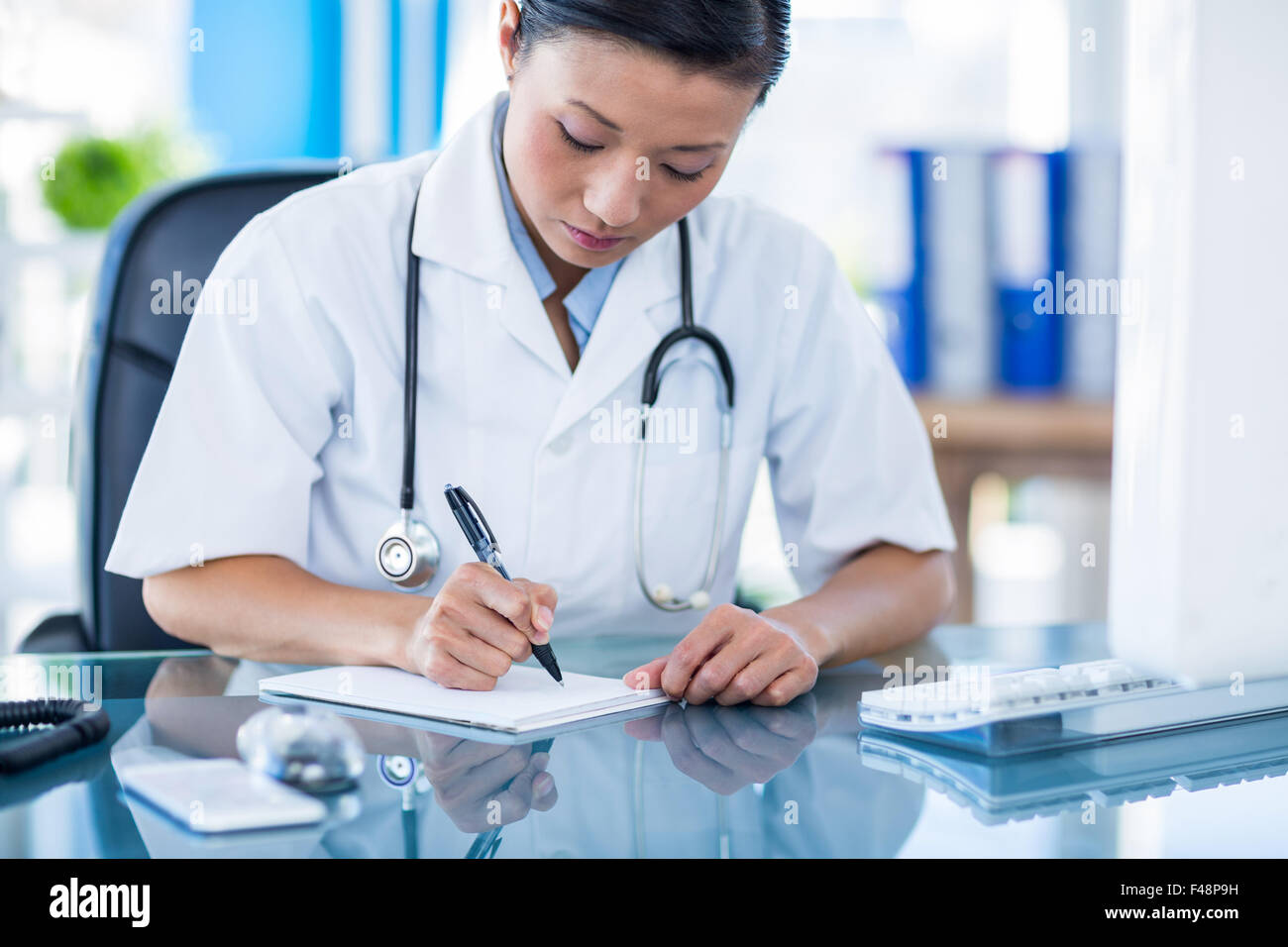 Concentrated doctor writing on notebook Stock Photo - Alamy
