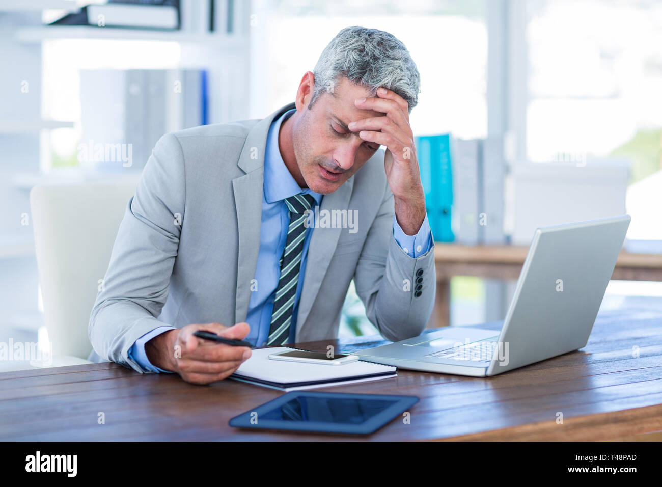 Irritated businessman trying to work Stock Photo - Alamy