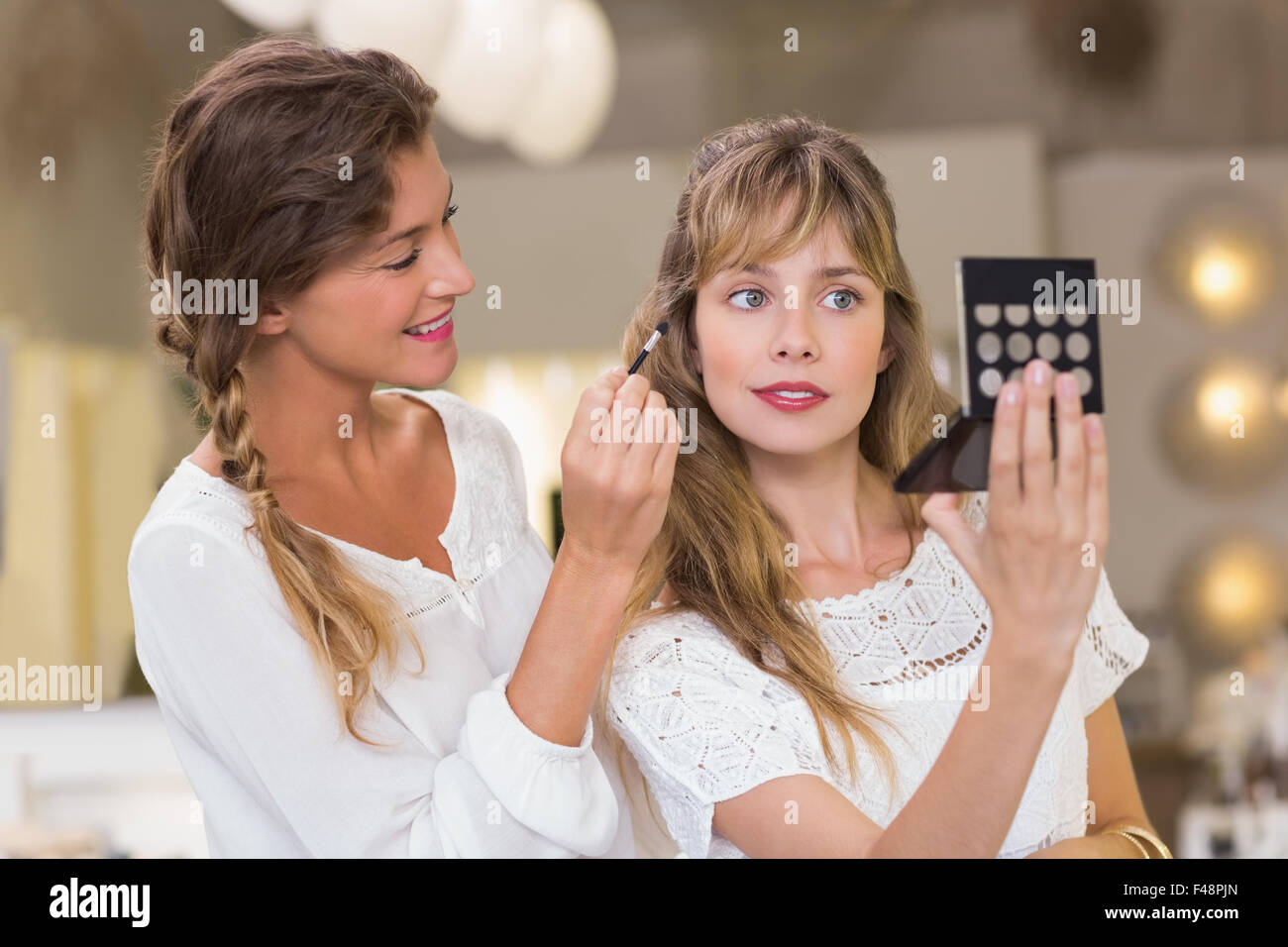 Employee applying makeup on costumer Stock Photo - Alamy