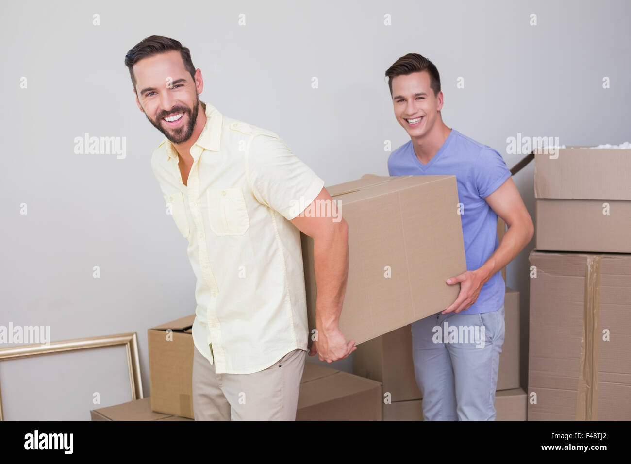 Happy homosexual couple holding box Stock Photo - Alamy