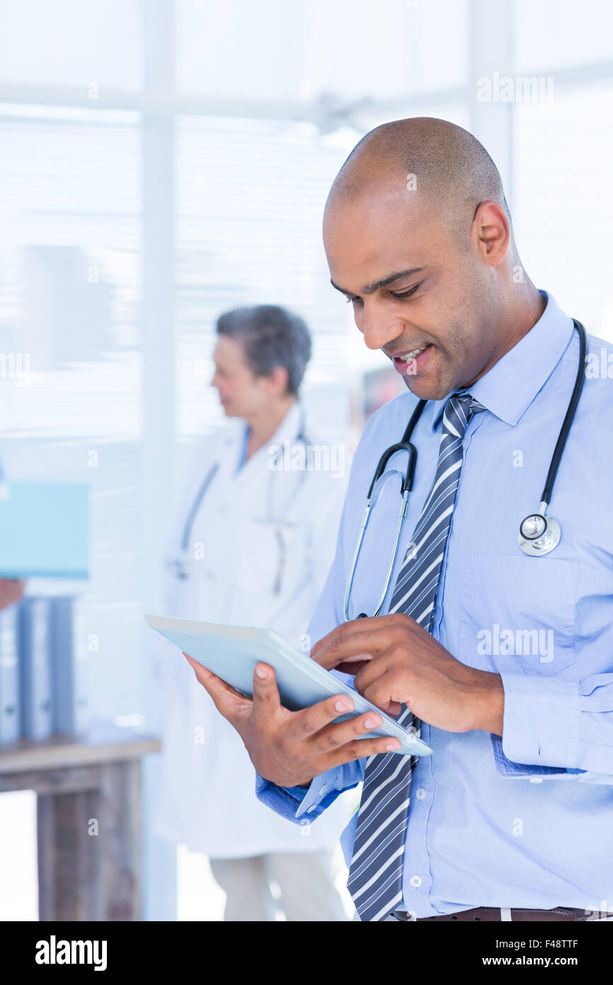 Smiling doctor using his tablet Stock Photo - Alamy