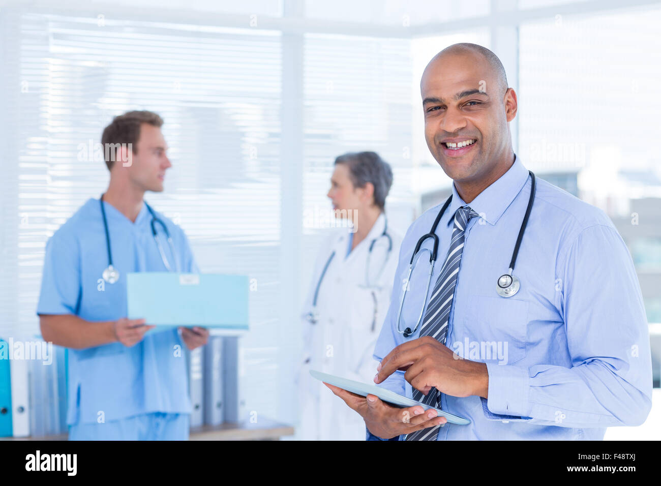 Smiling doctor using his tablet Stock Photo - Alamy