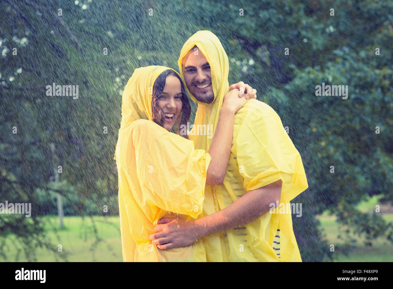 Cute couple wearing protection cape and hugging under the rain Stock ...
