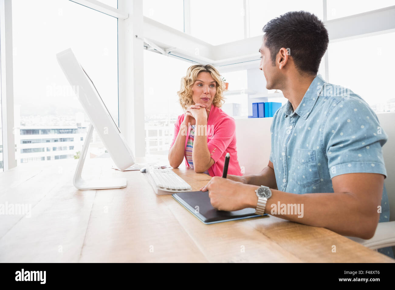 Colleagues speaking together at desk Stock Photo - Alamy