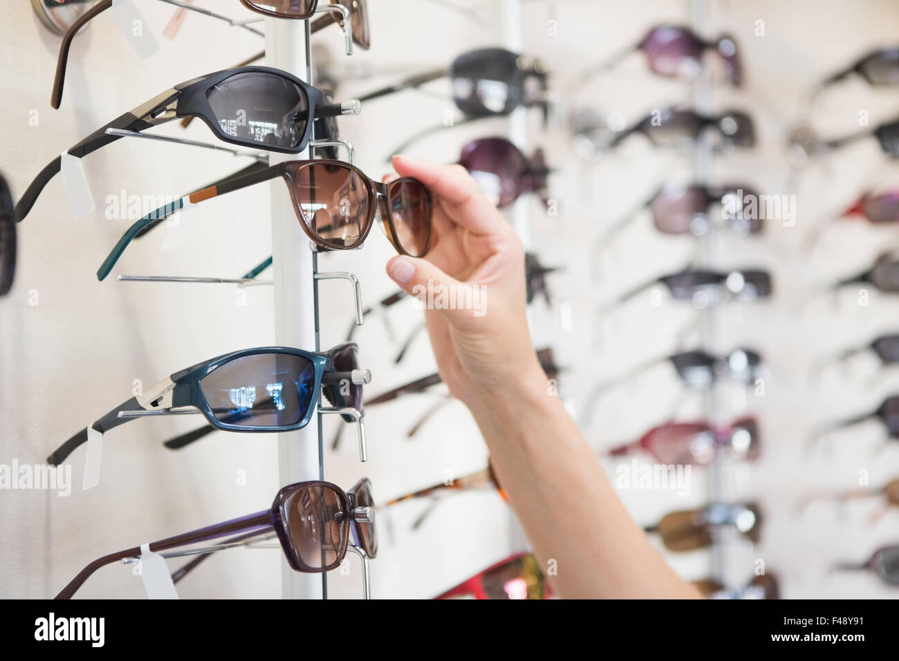 Woman taking sunglasses from the display Stock Photo - Alamy