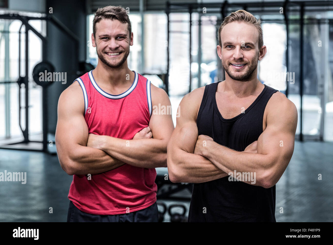 Two smiling muscular men with arms crossed Stock Photo - Alamy