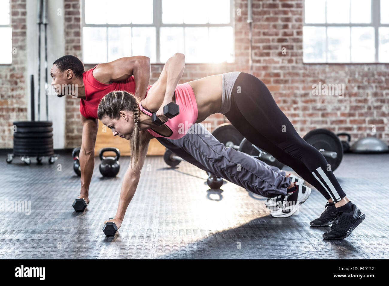 Fit couple doing push ups with dumbbells Stock Photo - Alamy