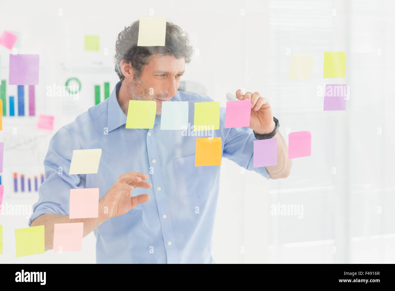 Creative businessman looking at post-it Stock Photo - Alamy