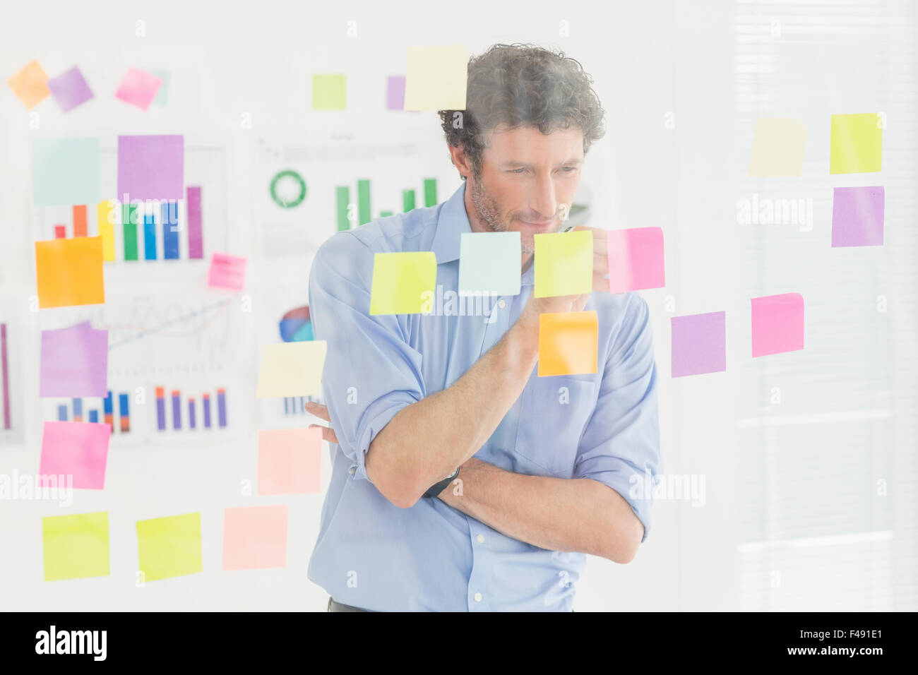 Creative businessman looking at post-it Stock Photo - Alamy