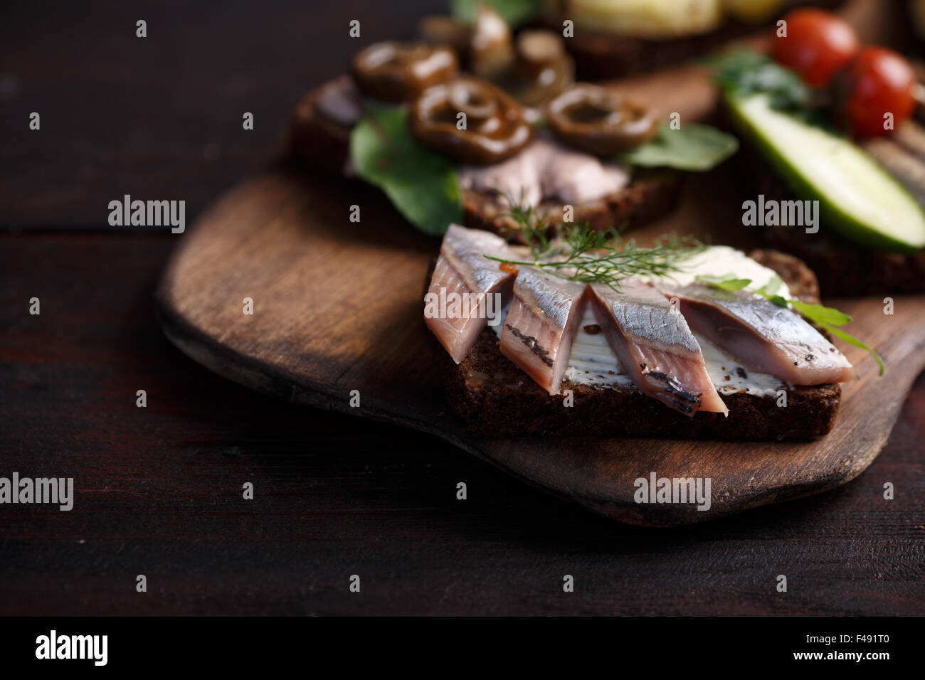 Variety of open sandwiches of buttered dense, dark rye bread with ...