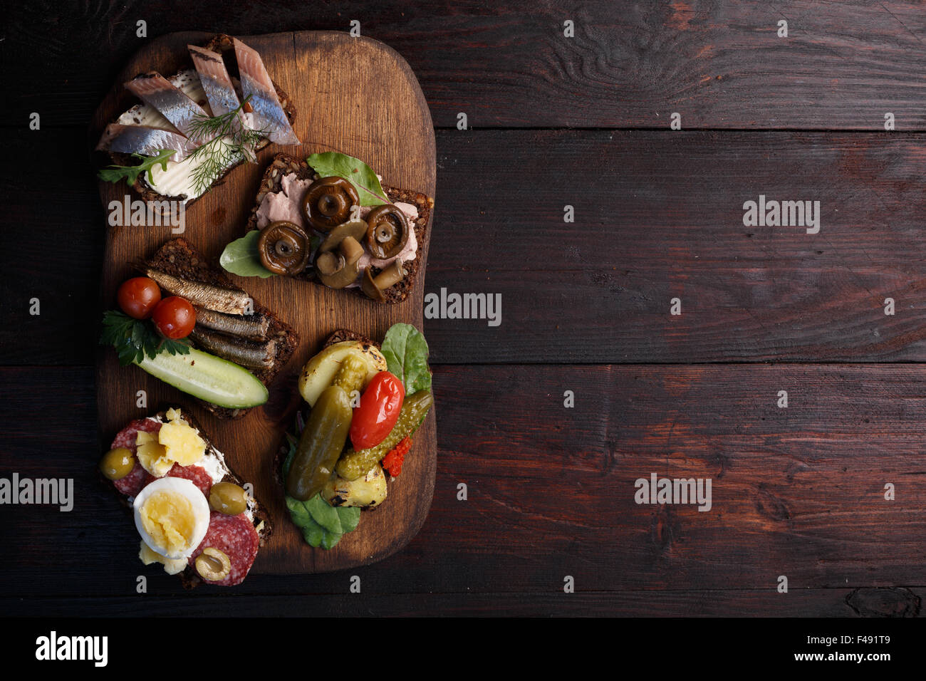 Variety of open sandwiches of buttered dense, dark rye bread with ...