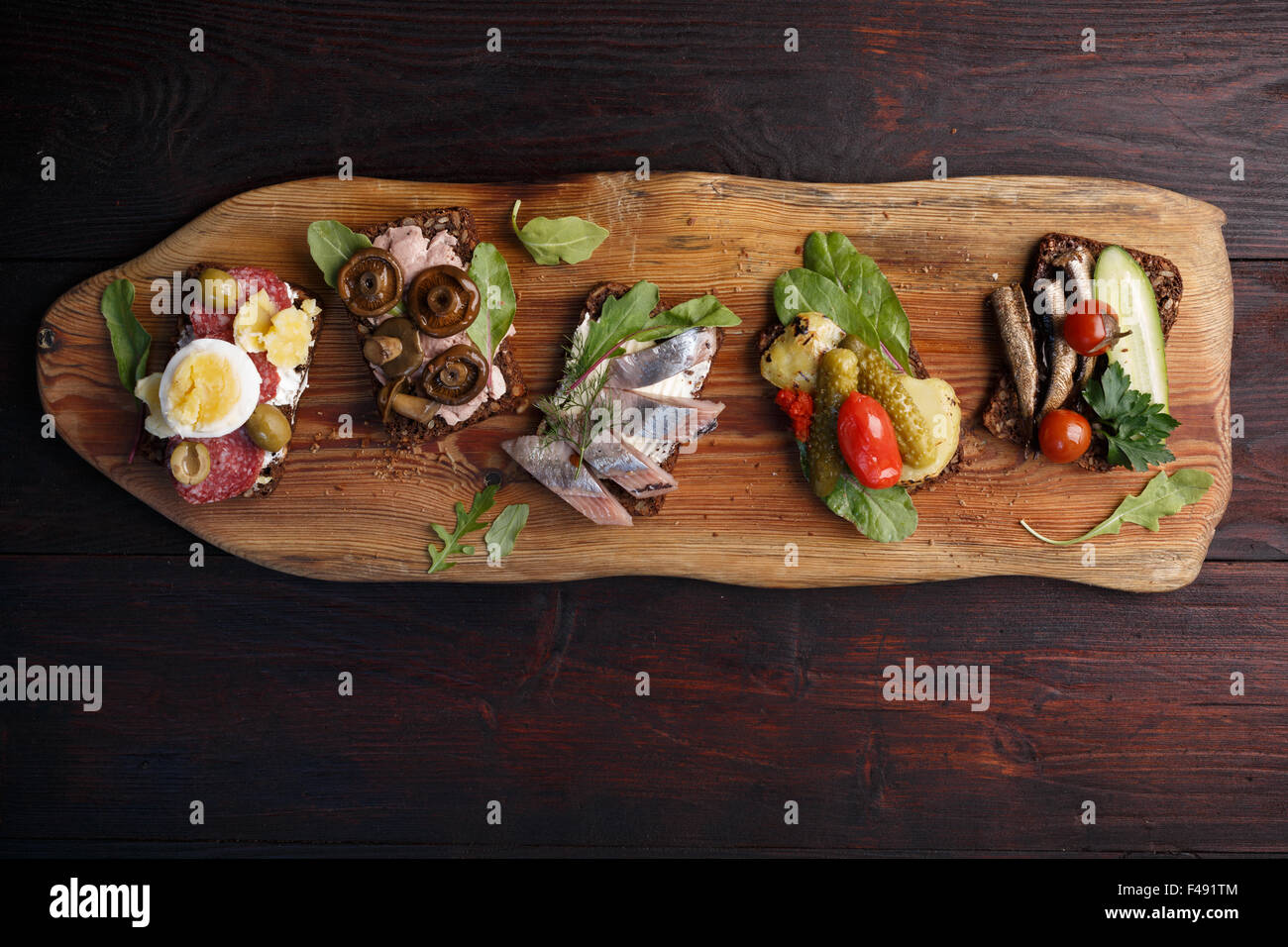 Variety of open sandwiches of buttered dense, dark rye bread with ...