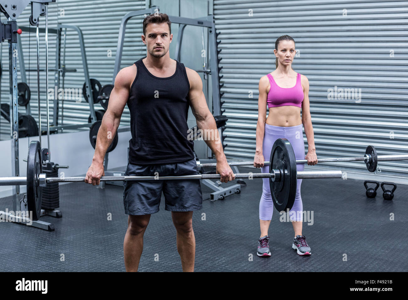 Muscular couple lifting weight together Stock Photo - Alamy