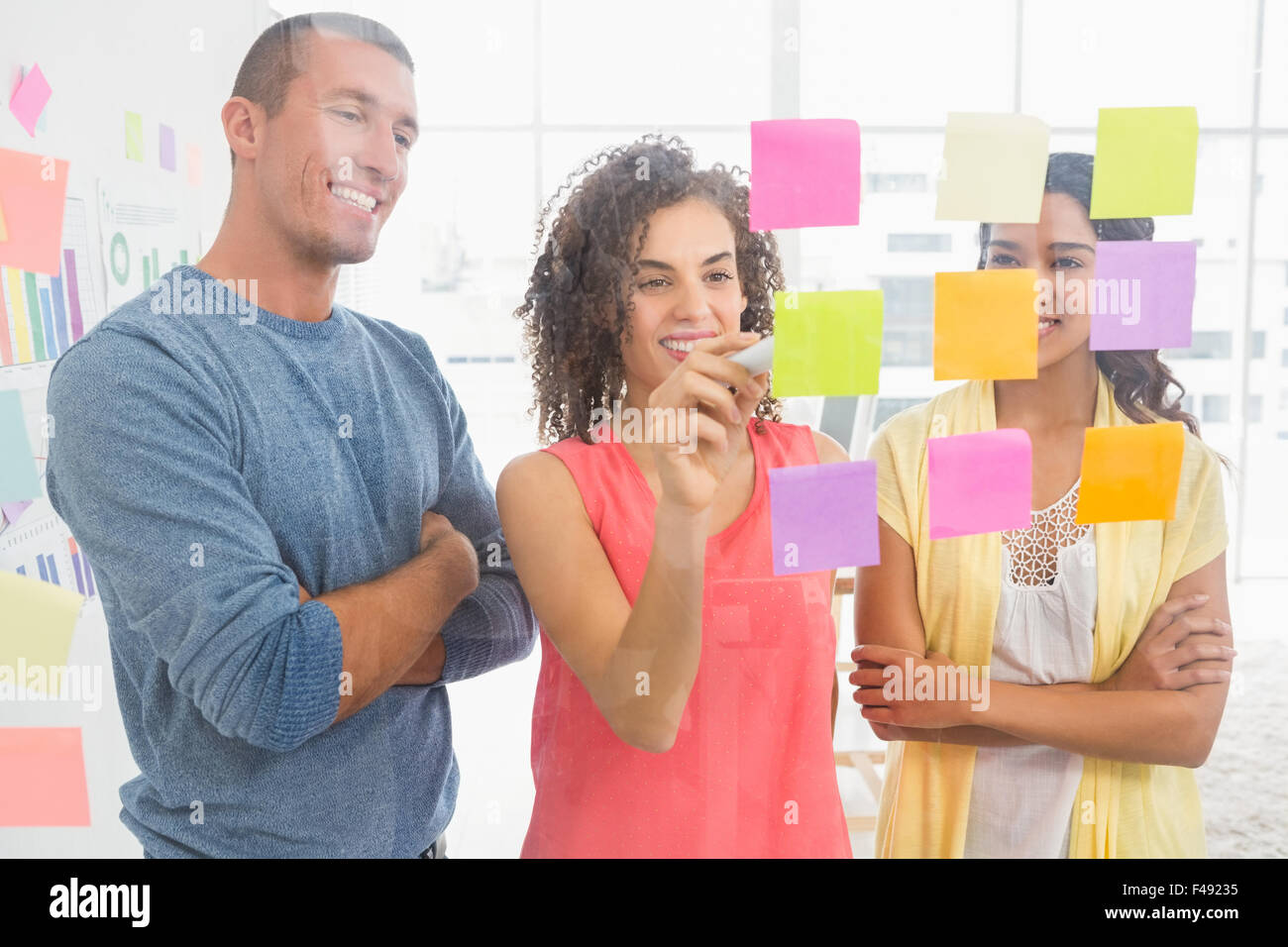 Smiling coworkers writing on sticky notes Stock Photo - Alamy