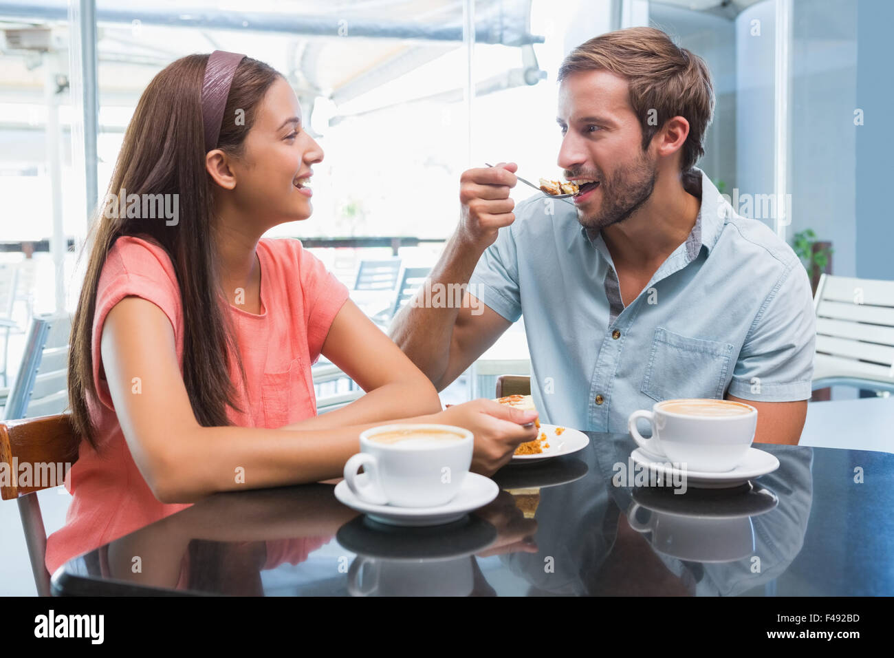 Young happy couple eating cake together Stock Photo - Alamy