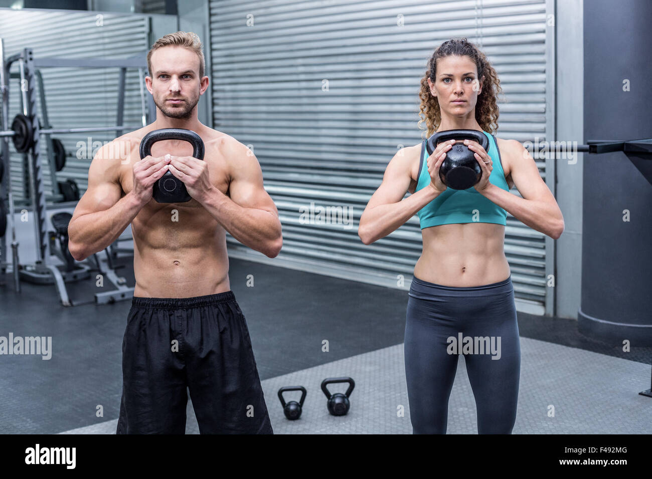 Muscular couple exercising with kettlebells Stock Photo - Alamy