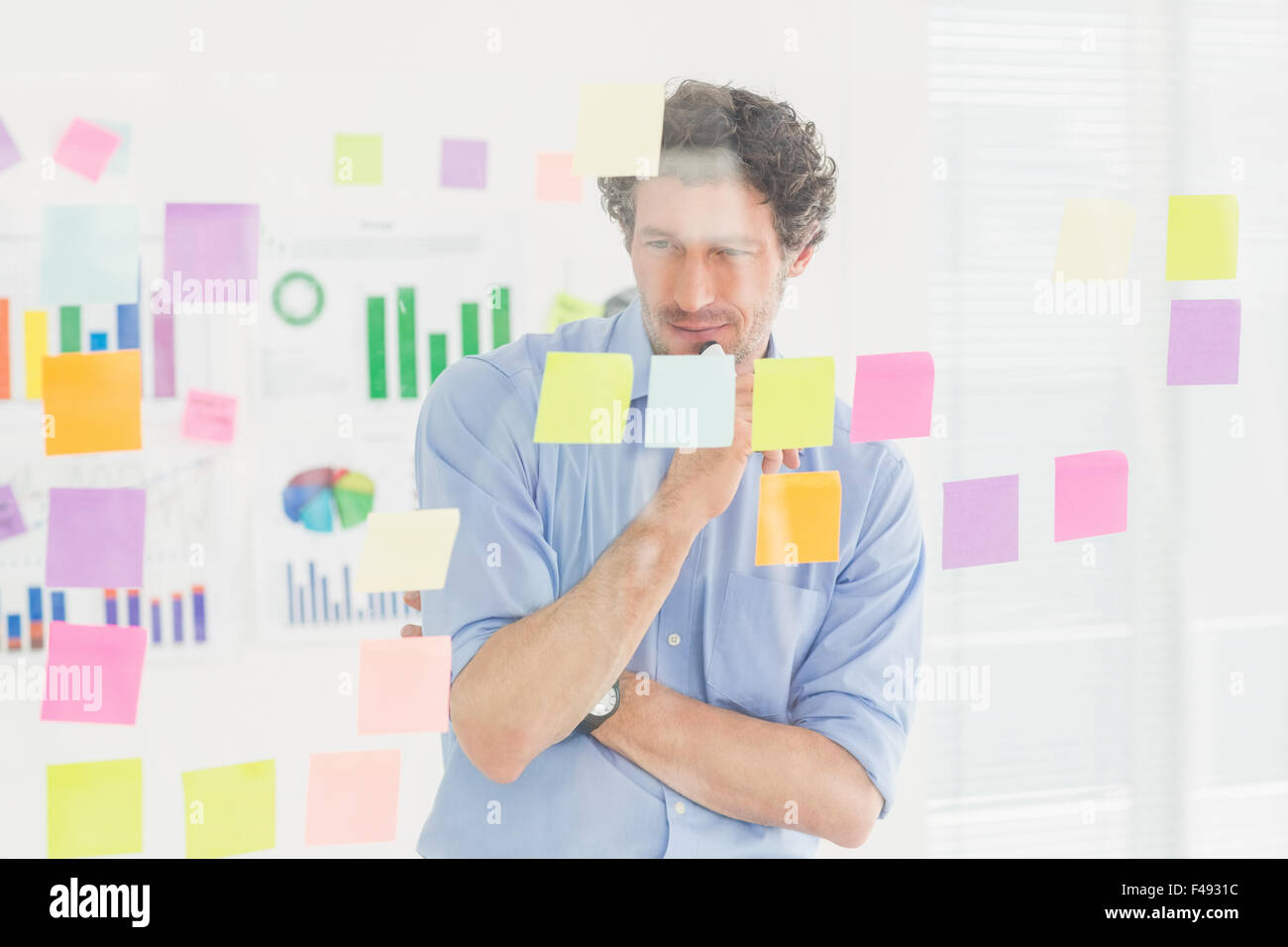 Creative businessman looking at post-it Stock Photo - Alamy