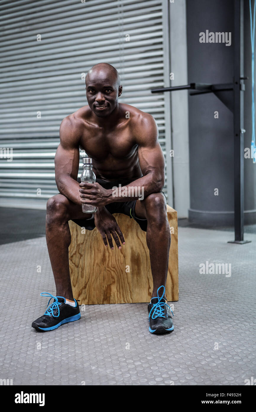 Young Bodybuilder sitting on a wooden Block Stock Photo - Alamy