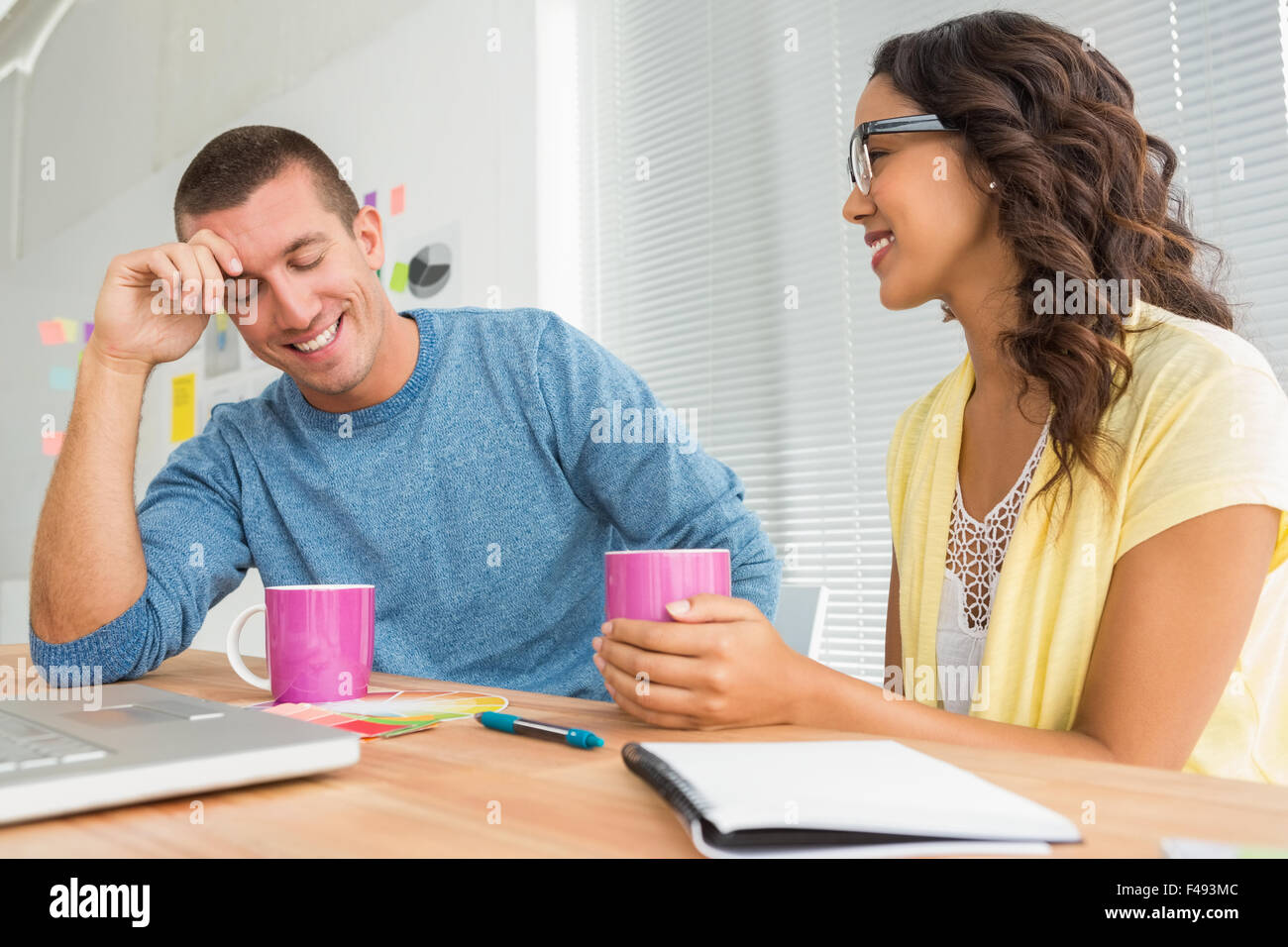 Smiling colleagues speaking together at desk Stock Photo - Alamy