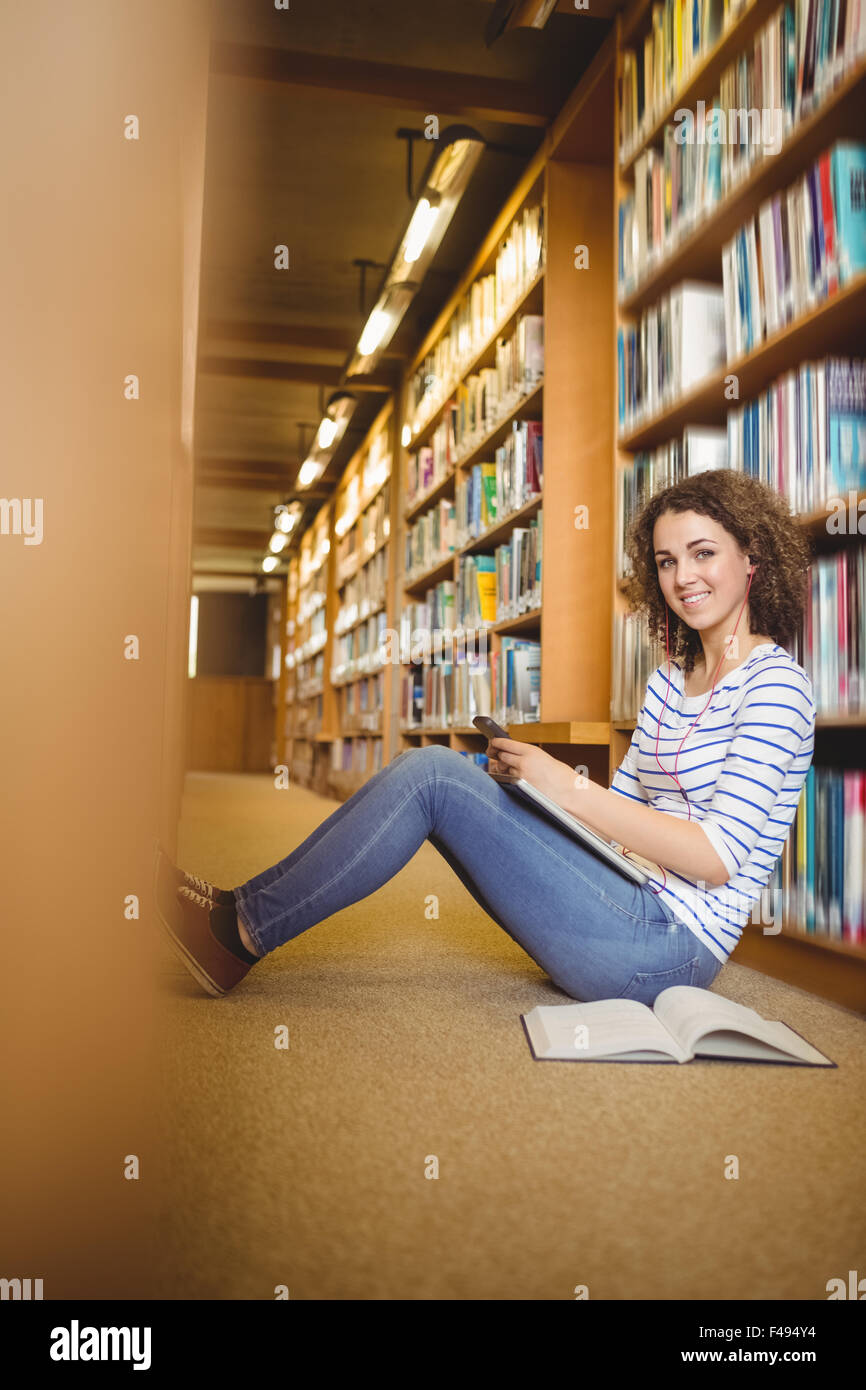 Pretty student in library sitting on the floor Stock Photo - Alamy