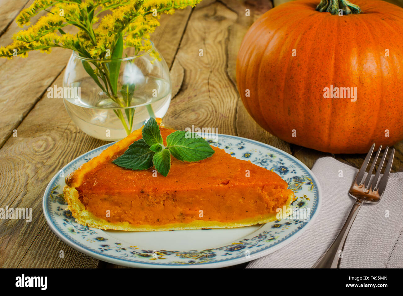 Thanksgiving pumpkin pie slice on white plate, linen napkin, vase ...