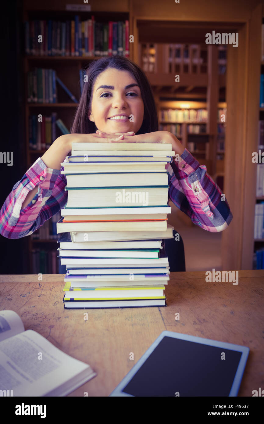 Cheerful female student leaning on book stack Stock Photo - Alamy