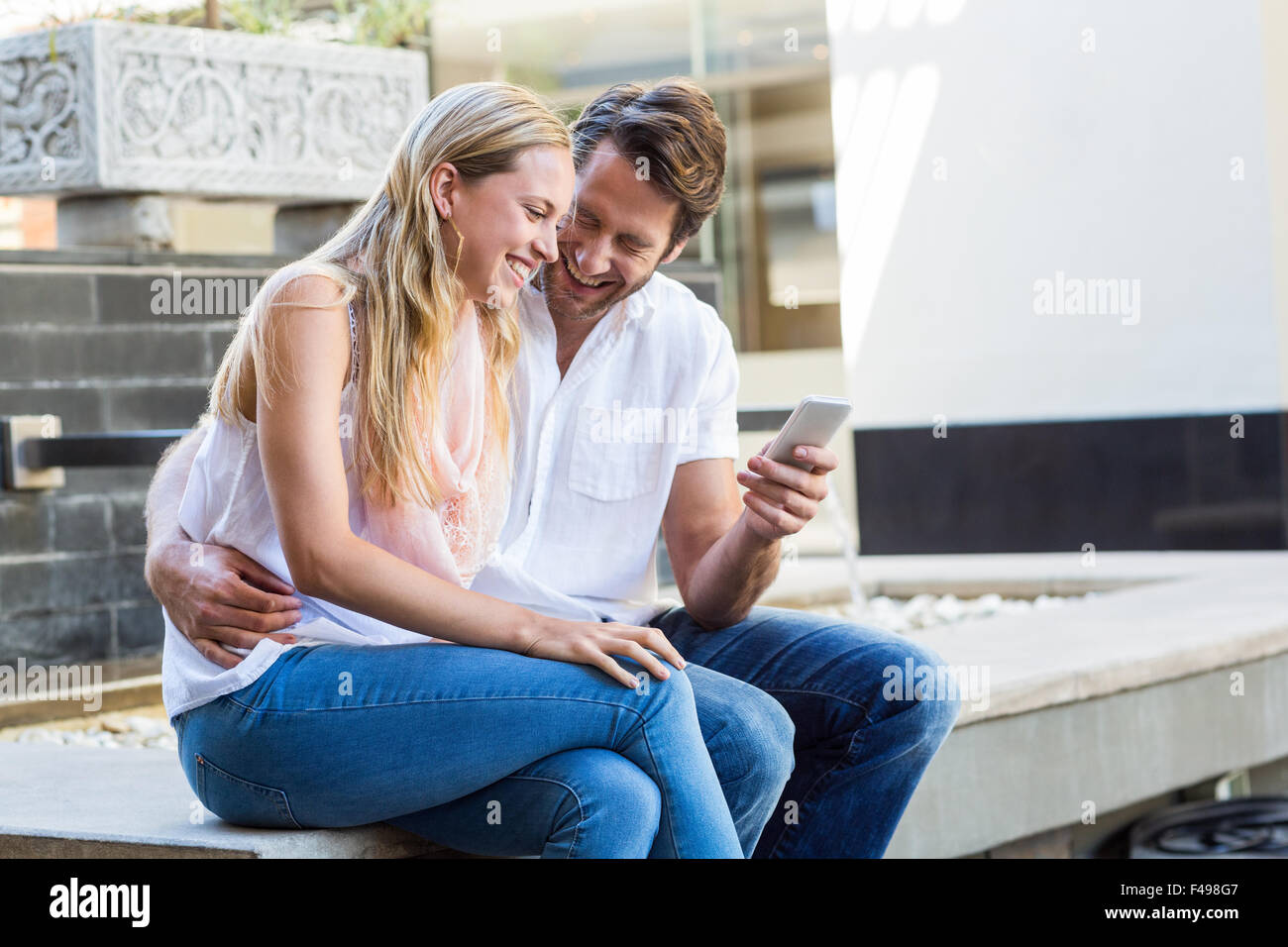 Happy couple sitting and laughing together Stock Photo - Alamy