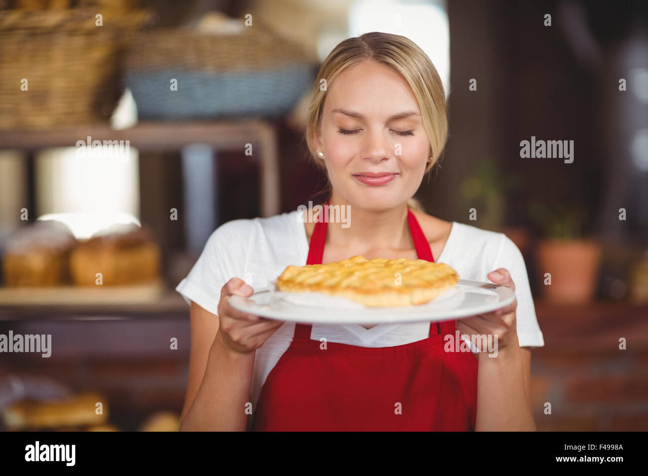 Pretty waitress smelling a plate of cake Stock Photo - Alamy
