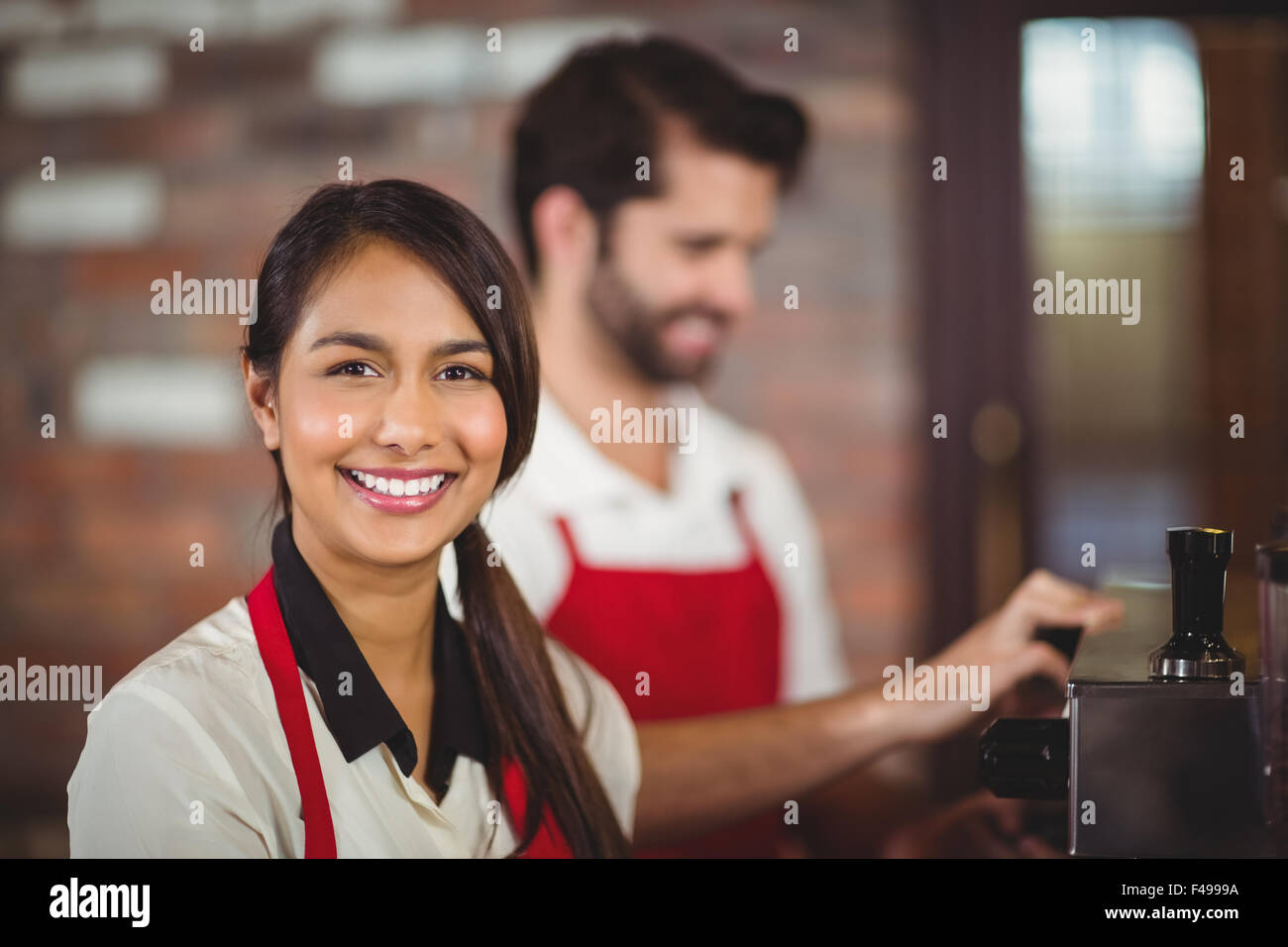 Smiling waitress using the coffee machine Stock Photo - Alamy