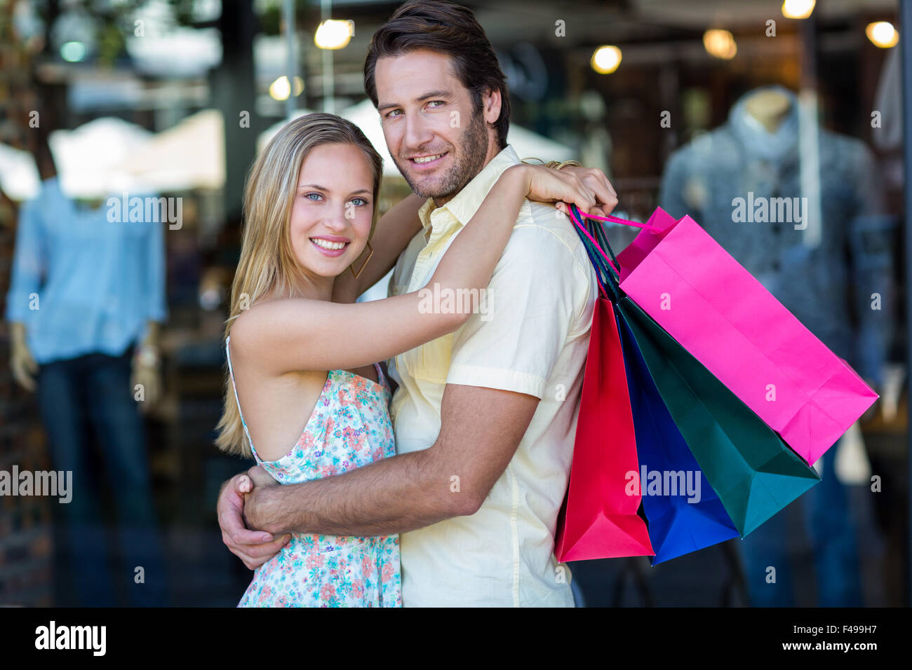 Smiling couple with shopping bags hugging Stock Photo - Alamy