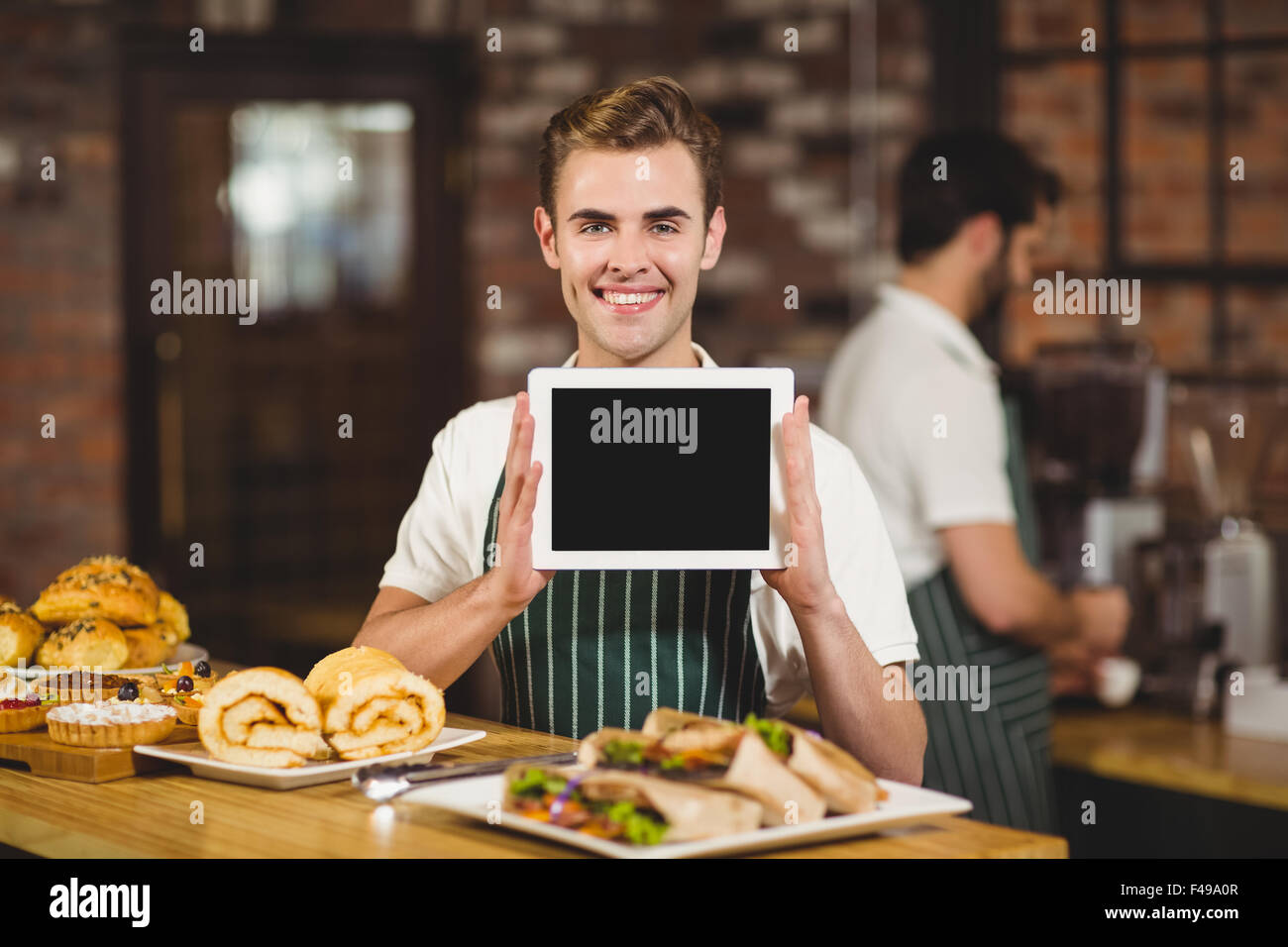 Smiling waiter holding a digital tablet Stock Photo - Alamy