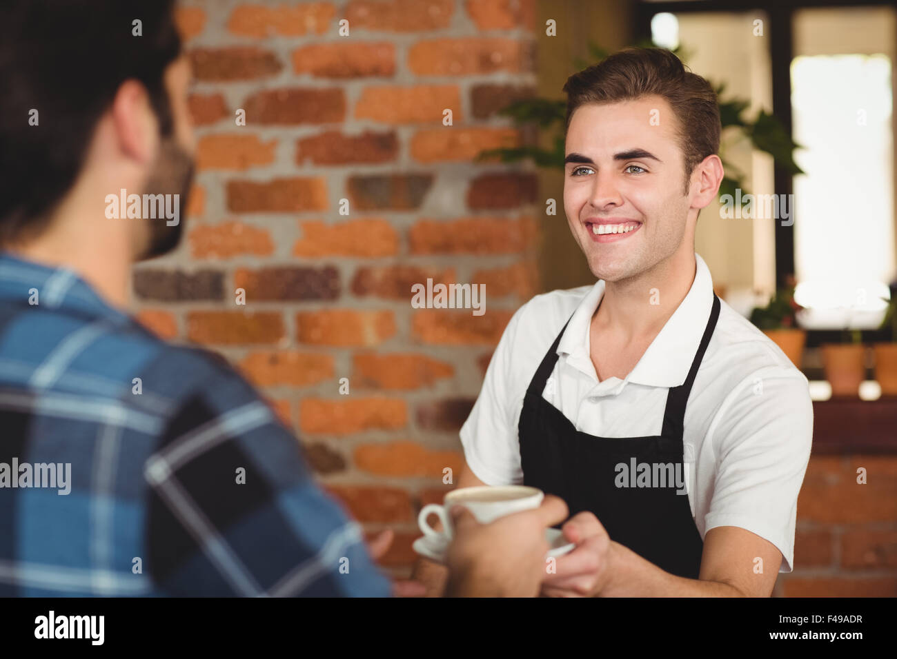 Smiling barista giving coffee to customer Stock Photo - Alamy