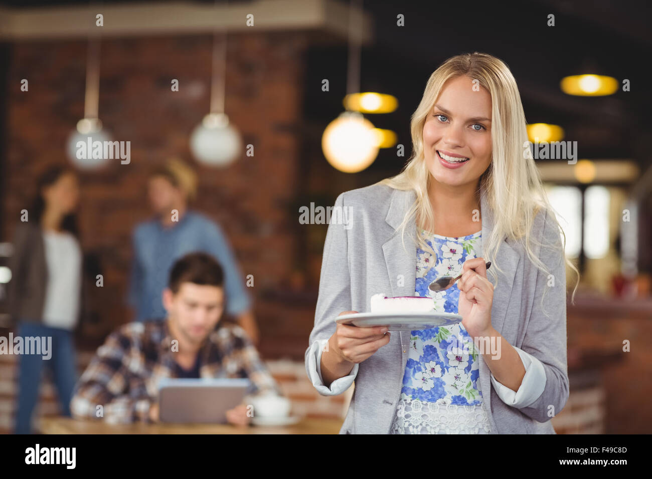 Smiling blonde woman eating cake Stock Photo - Alamy