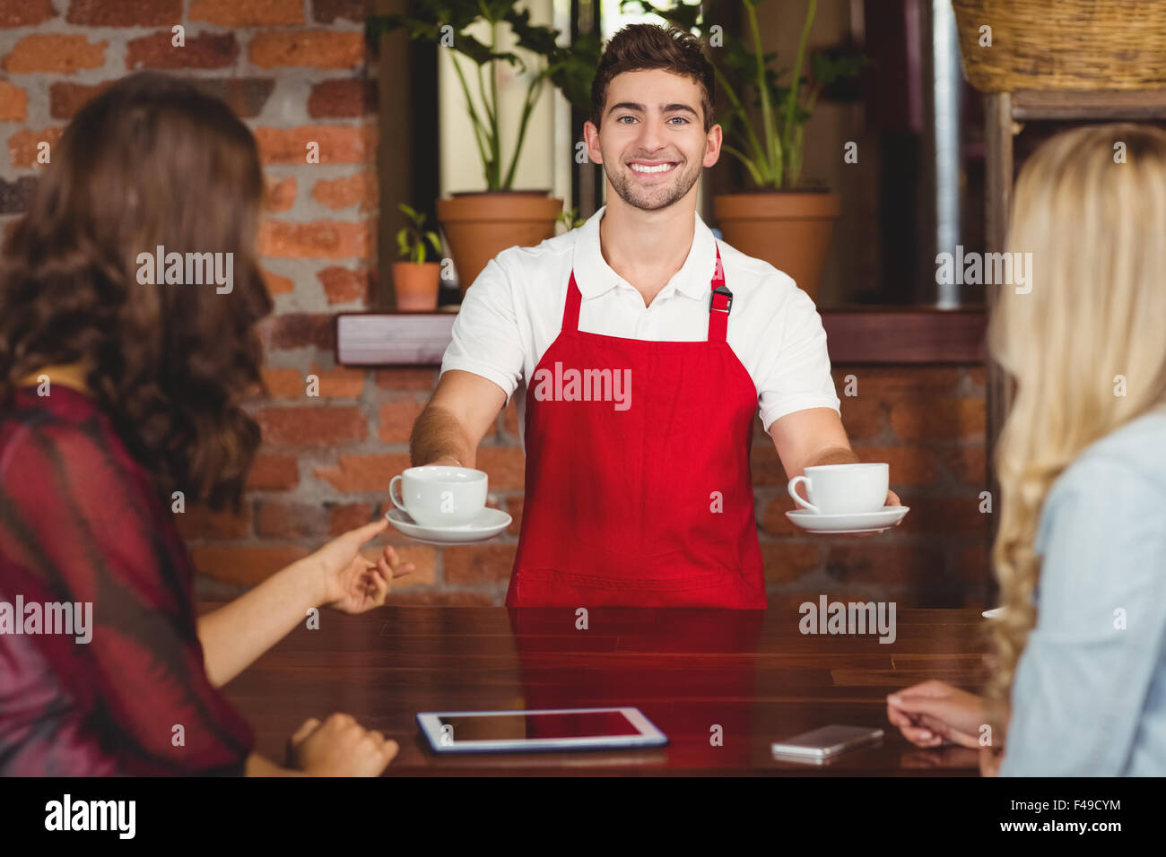 Smiling waiter serving coffees to customers Stock Photo - Alamy