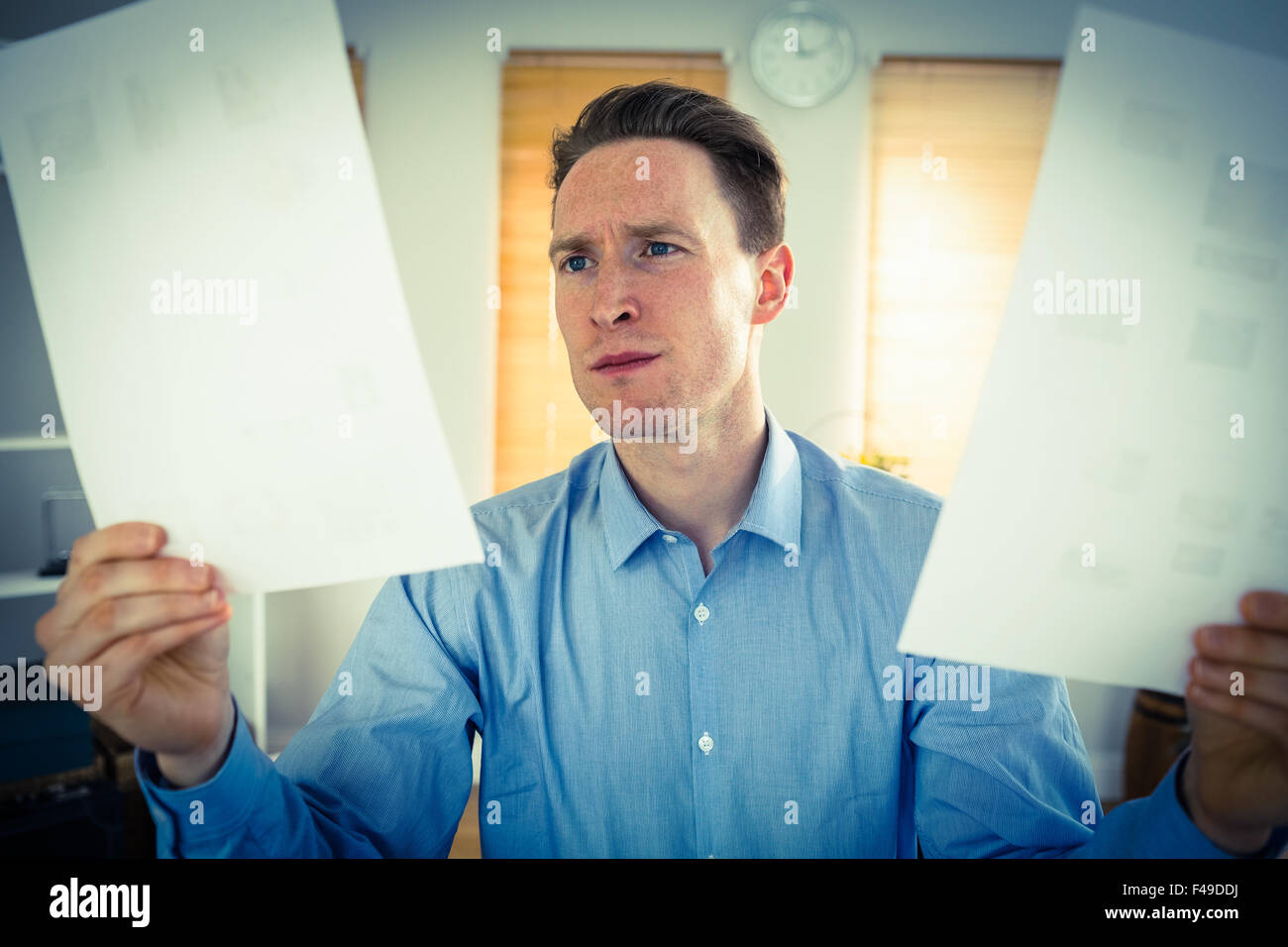 Serious businessman holding two paper sheets Stock Photo - Alamy