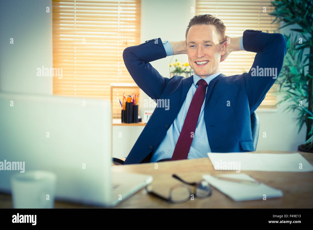 Relaxed businessman sitting back at desk Stock Photo - Alamy