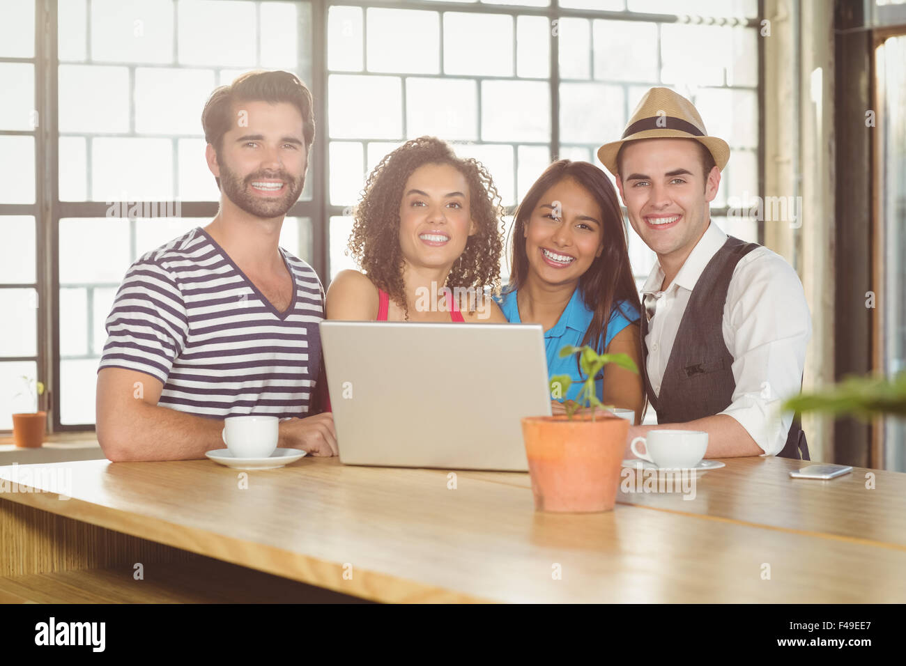 Smiling friends standing around laptop Stock Photo - Alamy