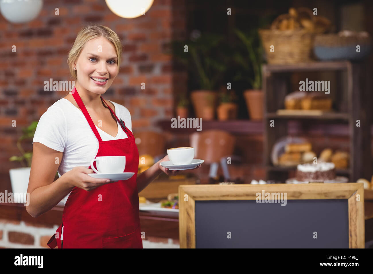 Pretty waitress holding two cups of coffees Stock Photo - Alamy