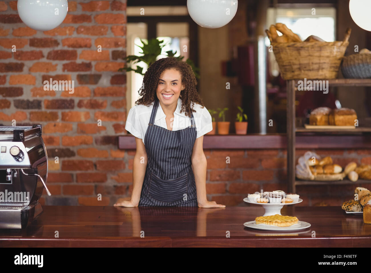 Smiling barista leaning on counter Stock Photo - Alamy