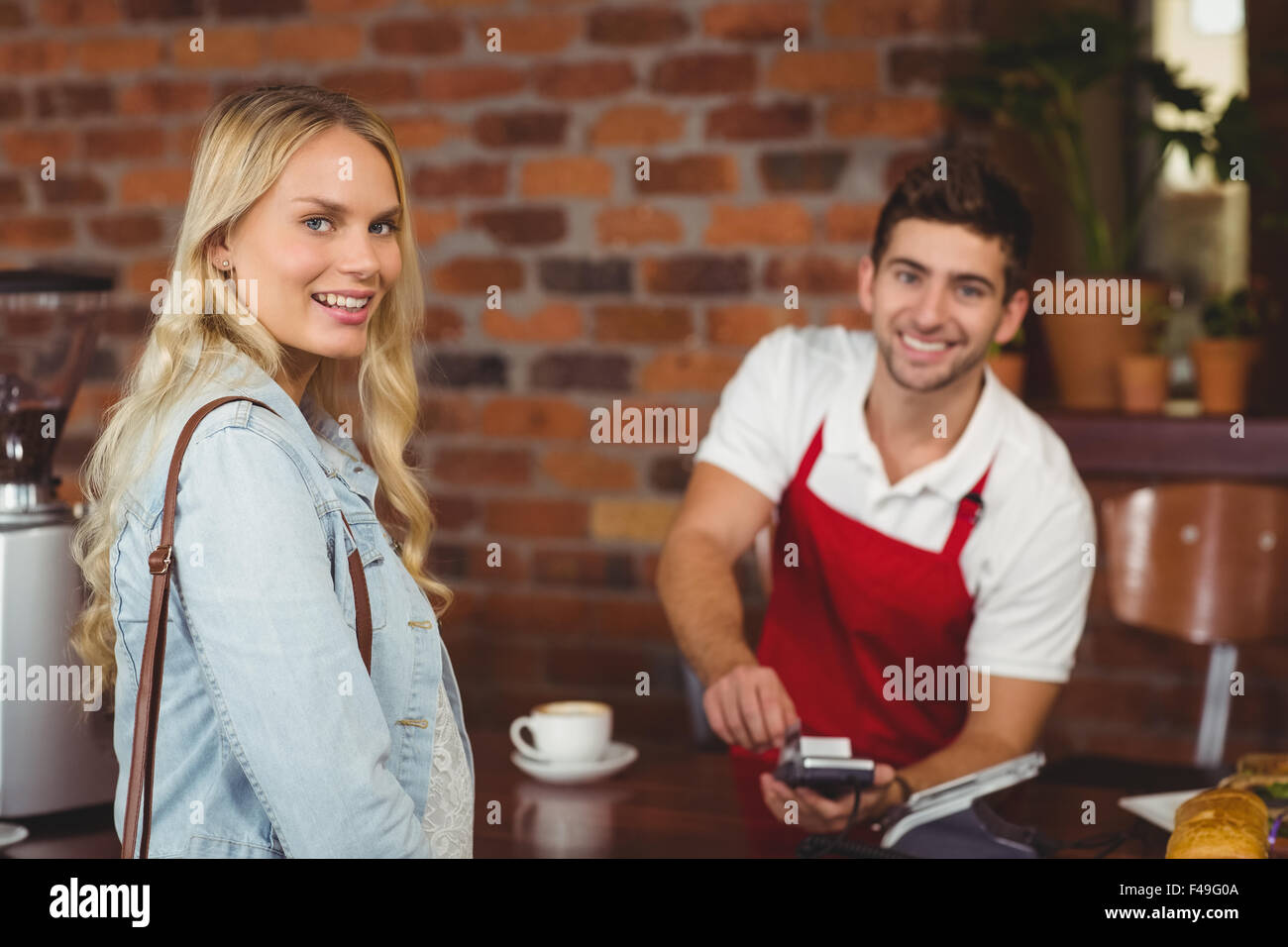 Smiling waiter using the pin terminal Stock Photo - Alamy