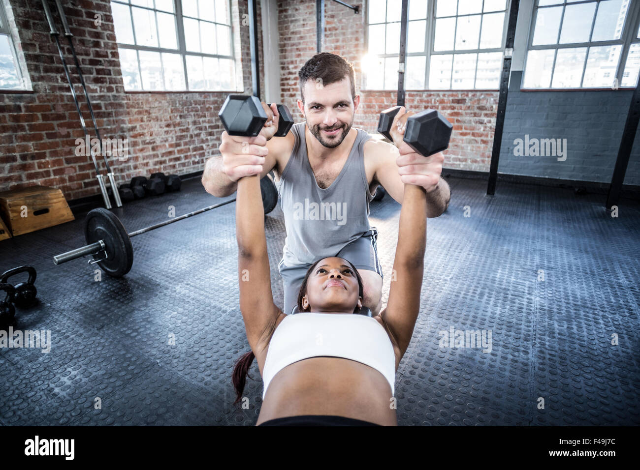 Personal trainer working with client holding dumbbell Stock Photo - Alamy