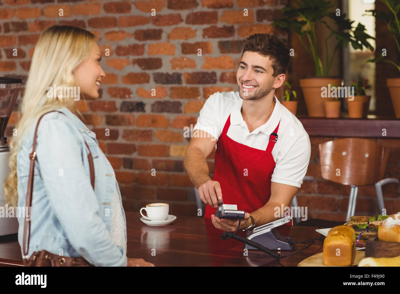 Smiling waiter using the pin terminal Stock Photo - Alamy