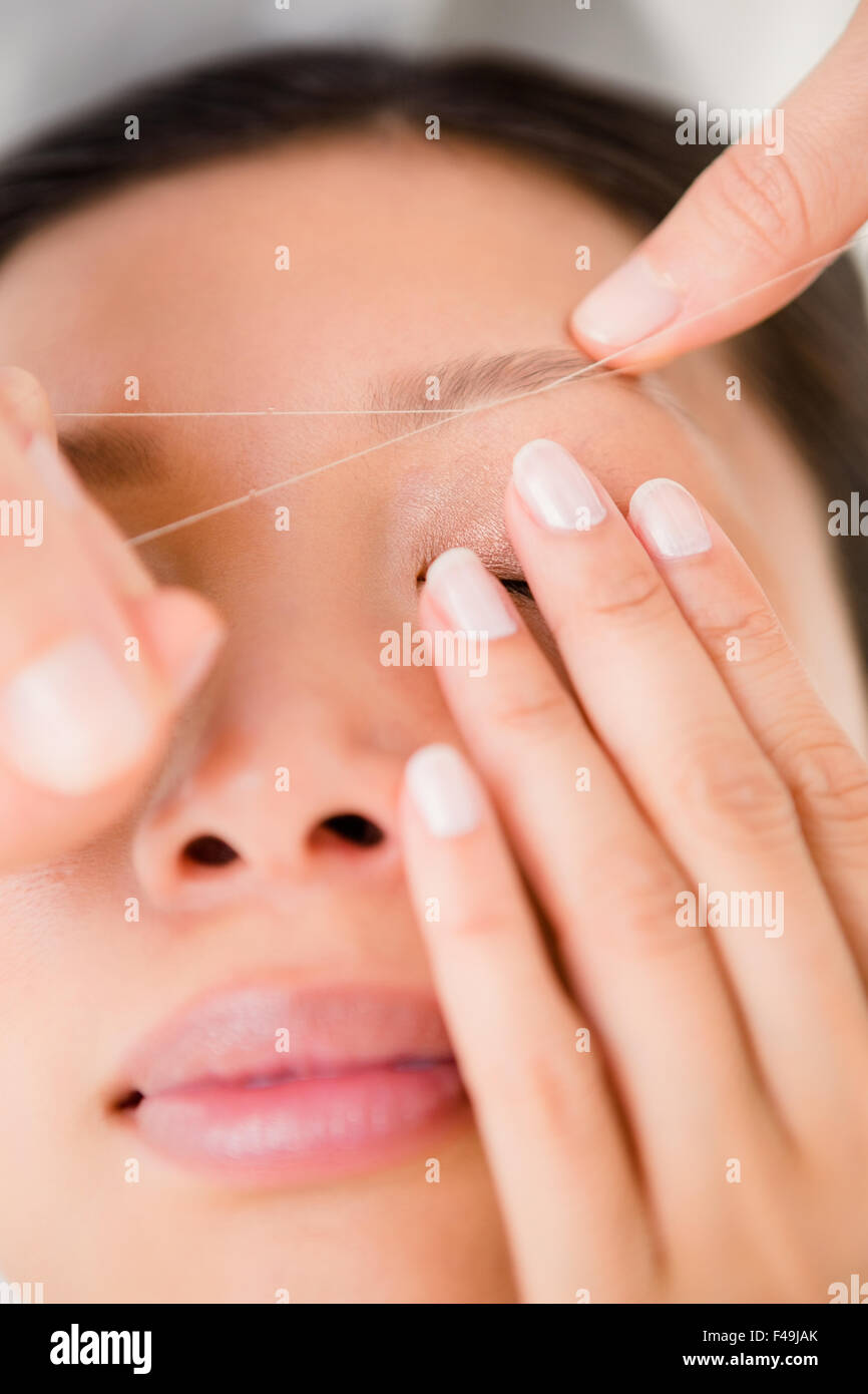 Hands threading beautiful womans eyebrow Stock Photo - Alamy