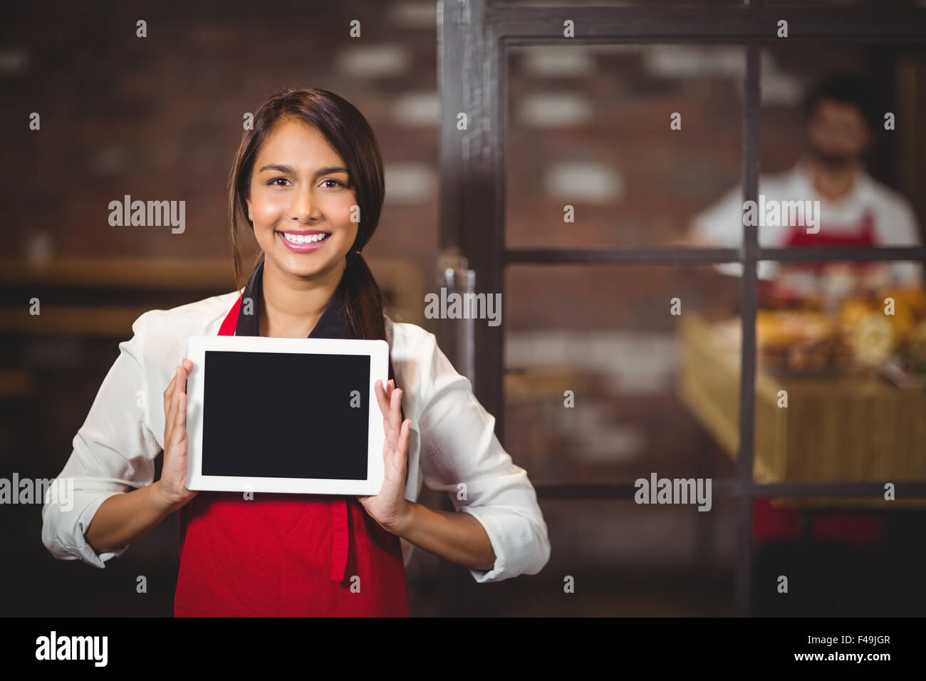 Smiling waitress showing a digital tablet Stock Photo - Alamy