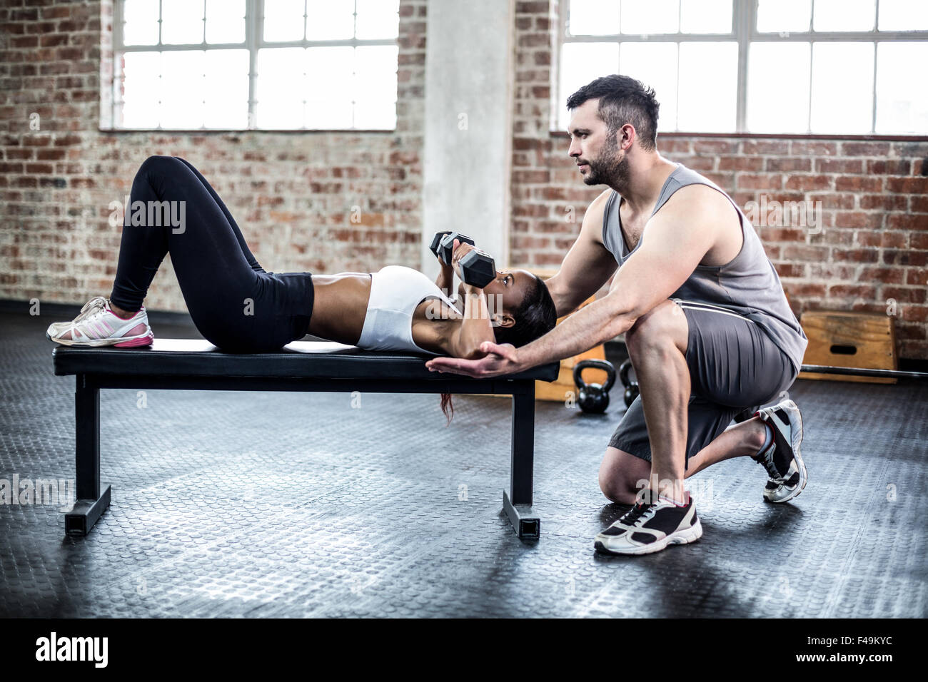 Personal trainer working with client holding dumbbell Stock Photo - Alamy