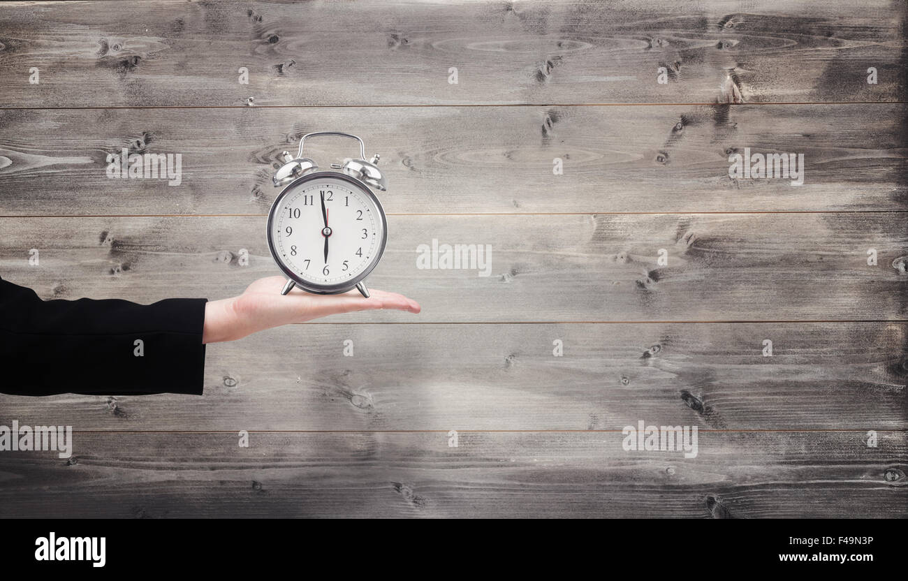 Composite image of hand holding alarm clock Stock Photo - Alamy